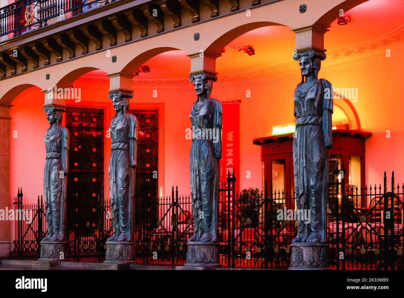 Goddess statues of a classical building facade lit at night Stock Photo ...