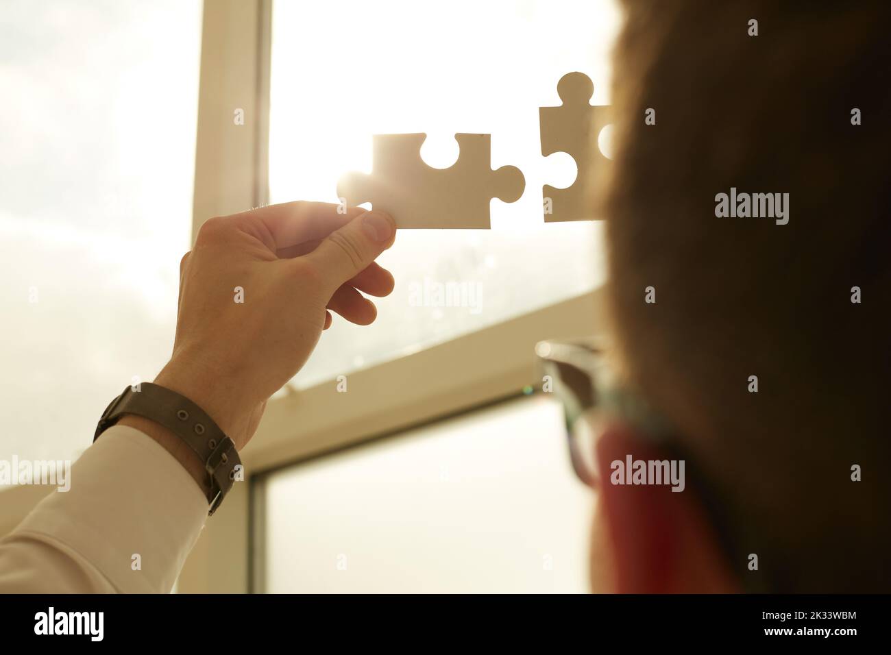 Businessman hands connecting puzzle pieces representing the merging of ...