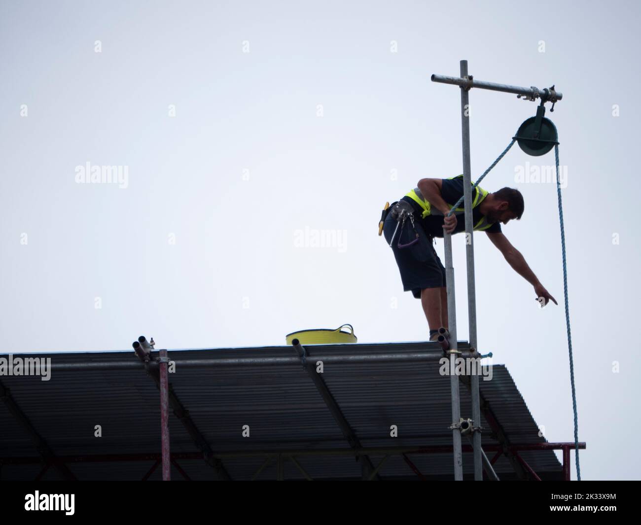builder, construction worker roofer, standing on rooftop scaffolding ...
