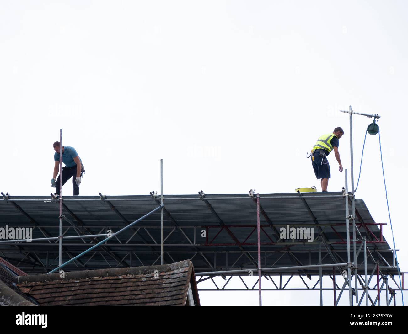 builder, construction worker roofer, standing on rooftop scaffolding ...