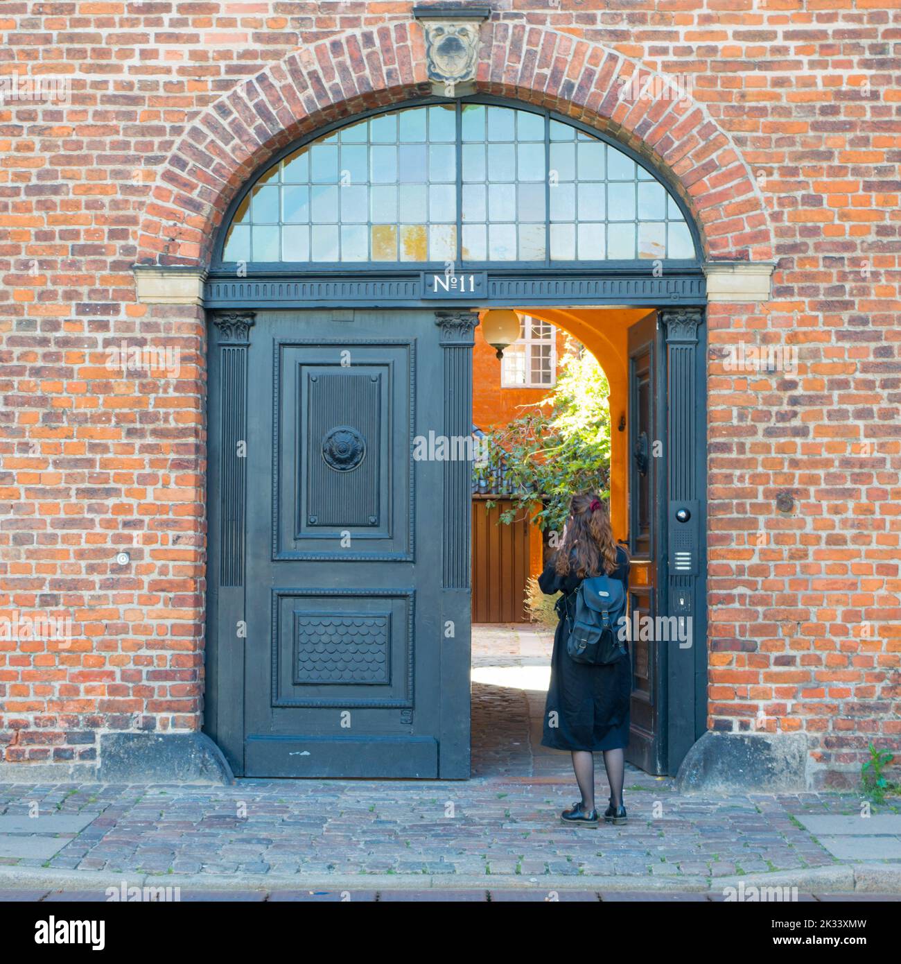 Girl in front of an open door taking photos of an atrium of a building ...