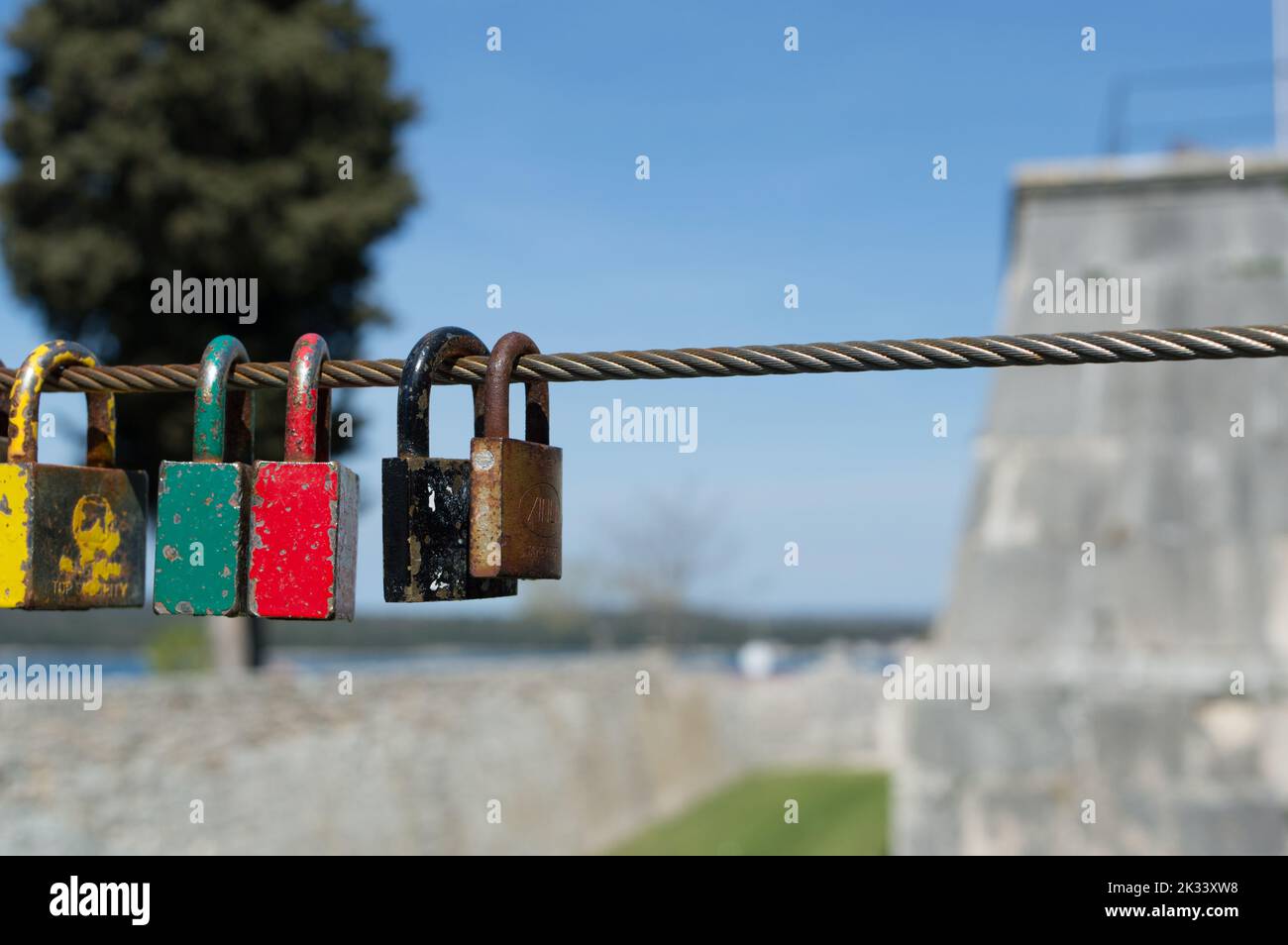 Old and rusty love padlocks locked on the steel cable, symbol of ...