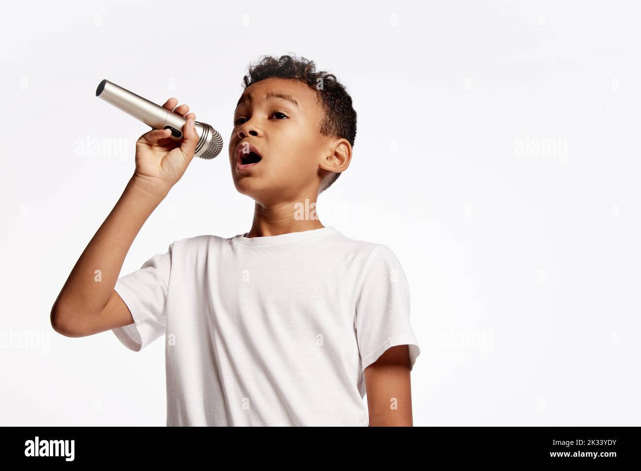 Portrait of little boy singing with microphone isolated on white ...