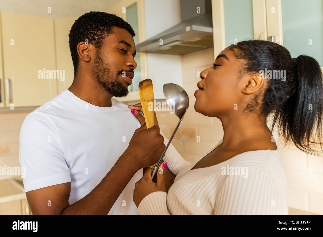 Hispanic Couple Singing Together Holding A Ladle Like A Microphone In