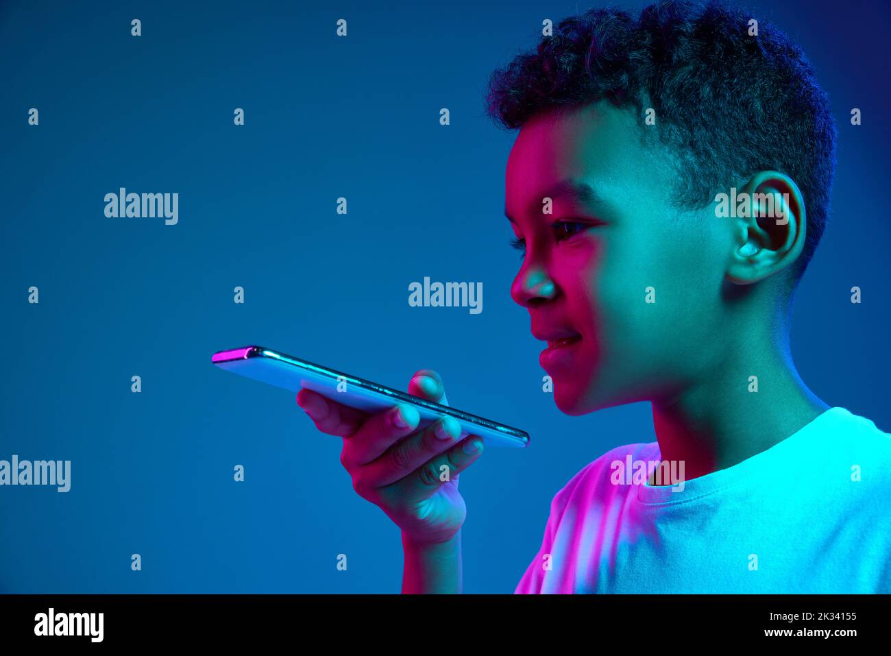 Cute little boy, kid using smartphone isolated over blue background in ...