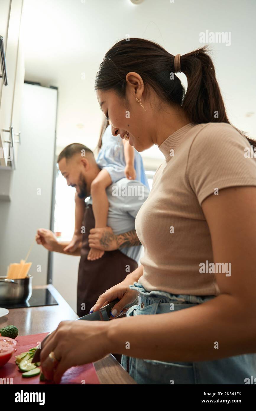 Mom cooks dinner, dad and daughter next each other in kitchen Stock ...