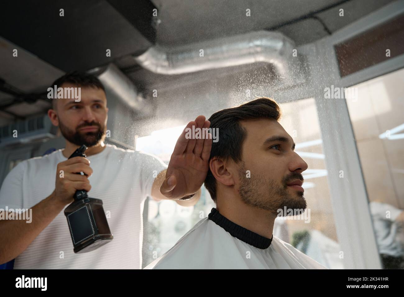 Attractive guy having his hair sprayed by a barber Stock Photo - Alamy