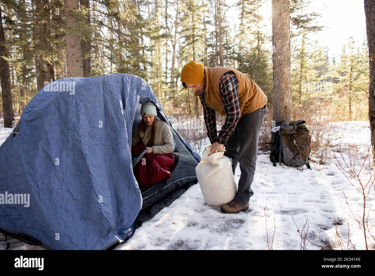Couple camping in snowy forest Stock Photo - Alamy