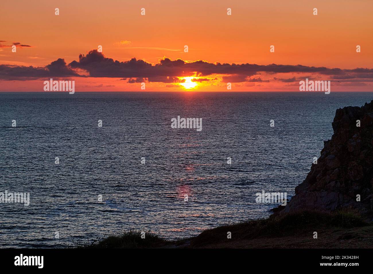 Sunset behind clouds on the Atlantic Ocean, rocky coast Pointe du Van ...
