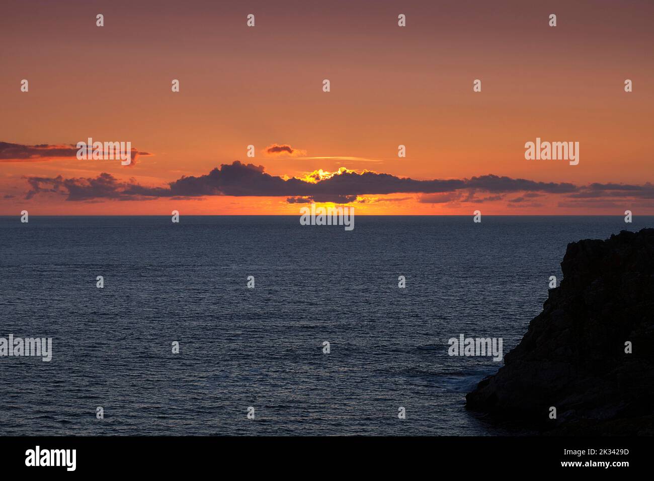 Sunset behind clouds on the Atlantic Ocean, rocky coast Pointe du Van ...