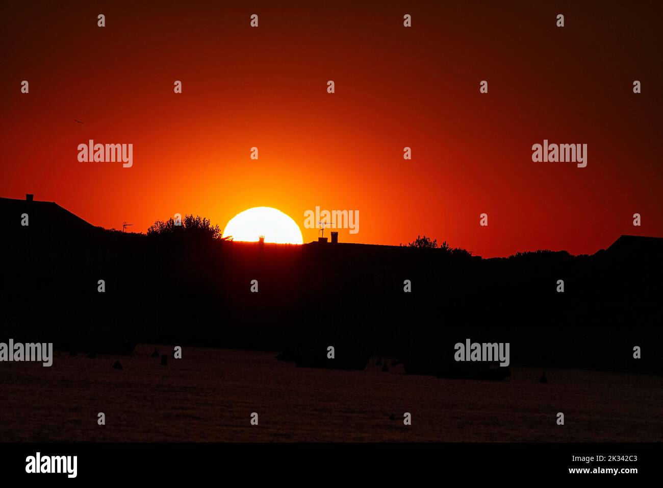 Red sunset behind house roofs, backlight, France Stock Photo - Alamy