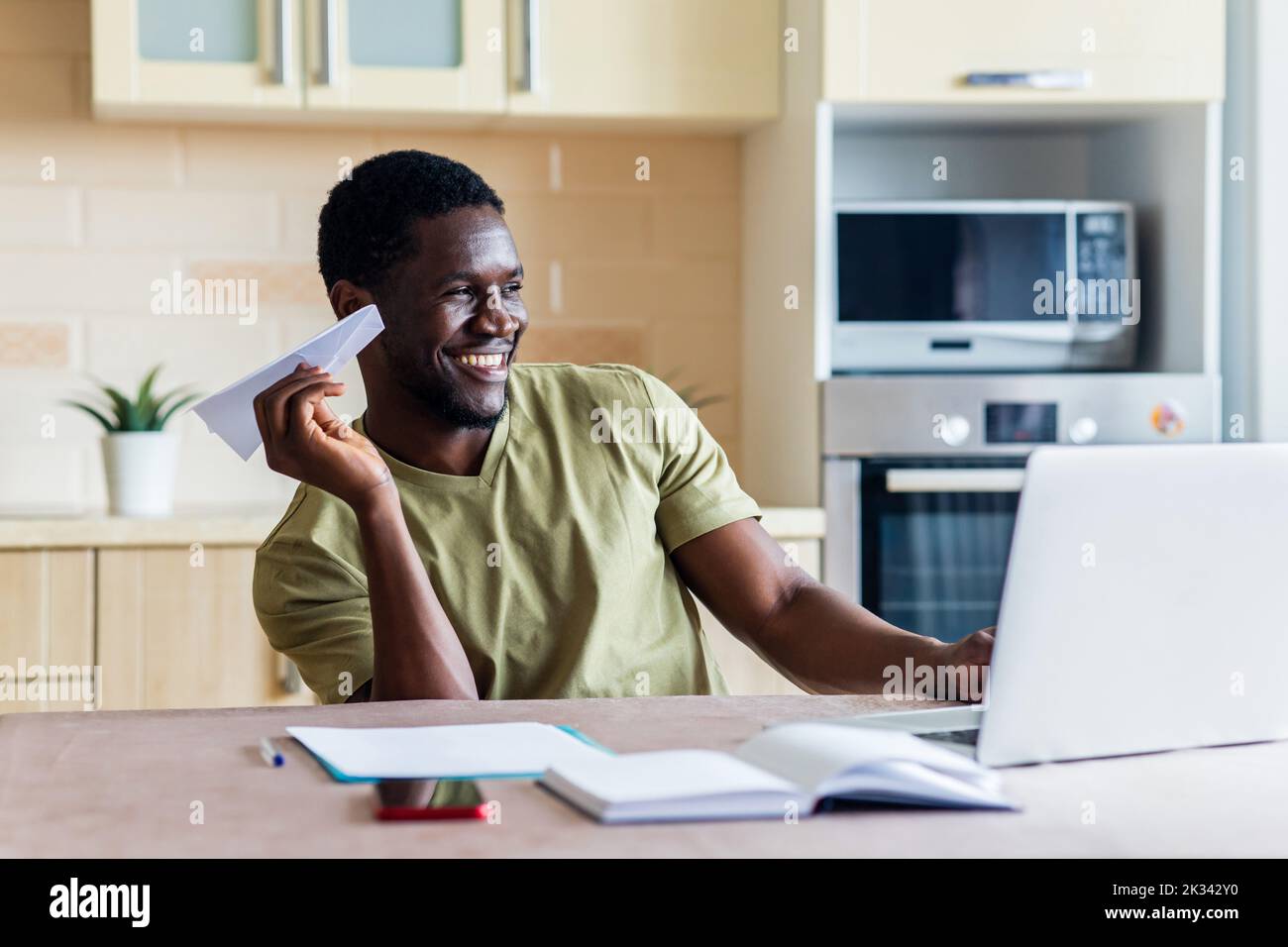 hispanic man throw paper plane and resting from paperwork in kitchen ...