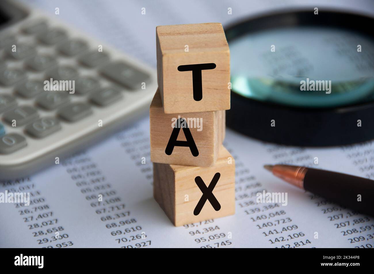 Tax word on wooden blocks with calculator, pen, magnifying glass and ...