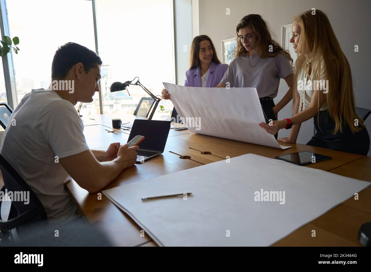 Four colleagues are studying a large document in the office Stock Photo ...