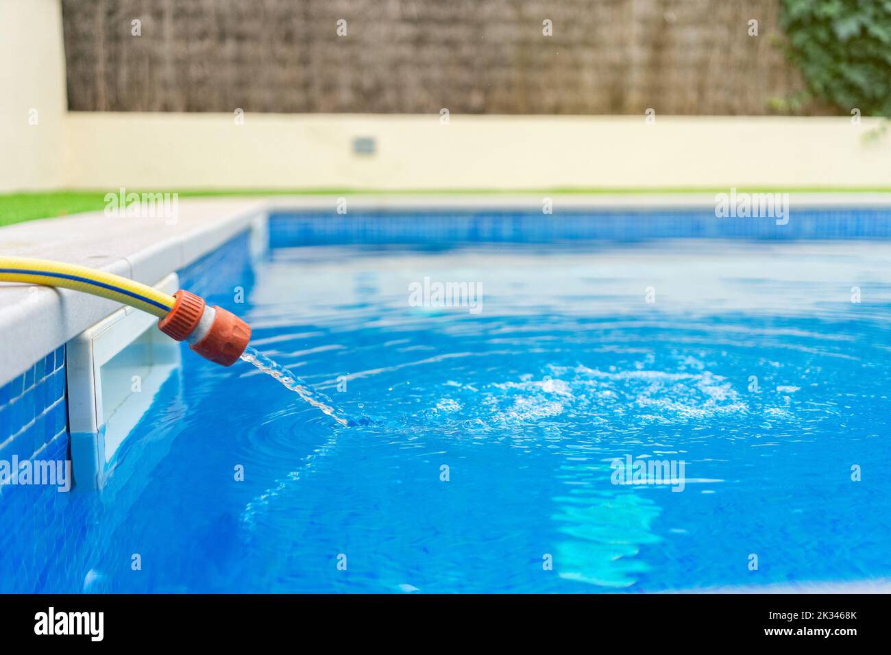 swimming pool being filled with water with a garden hose at summer ...