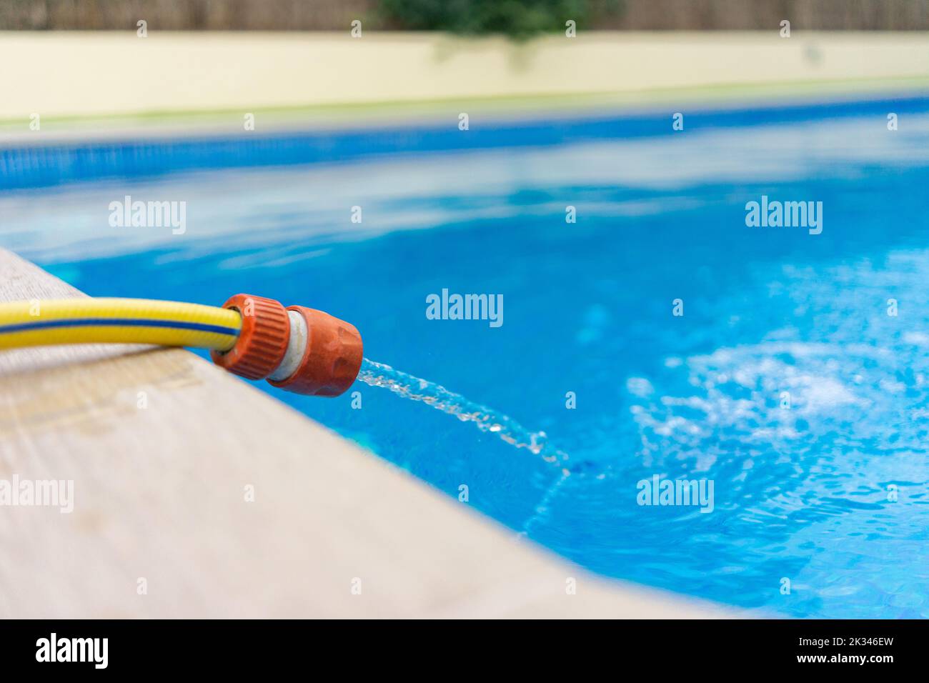 swimming pool being filled with water with a garden hose at summer ...