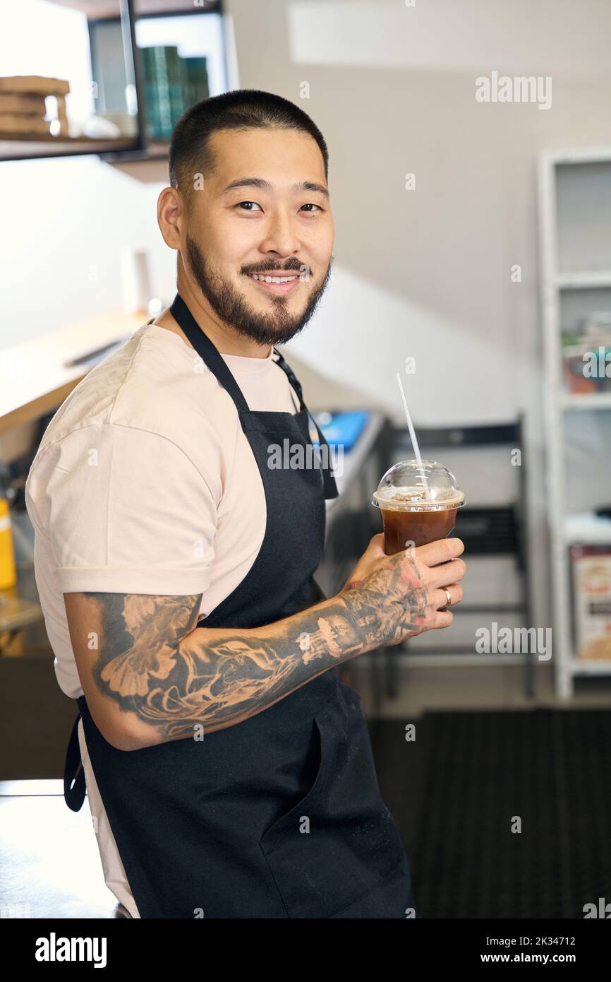 Good-looking guy working as barista and holding a drink Stock Photo - Alamy