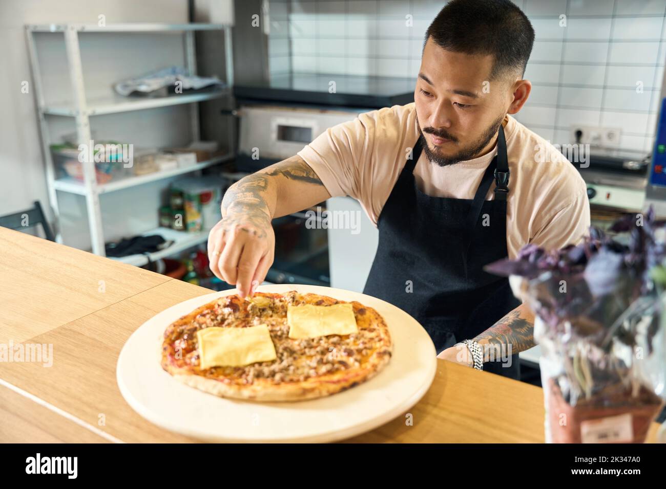 Focused cook putting finishing touches on fresh pizza Stock Photo - Alamy