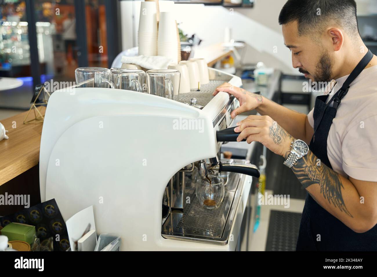 Concentrated barista preparing espresso next to a coffee-maker Stock ...