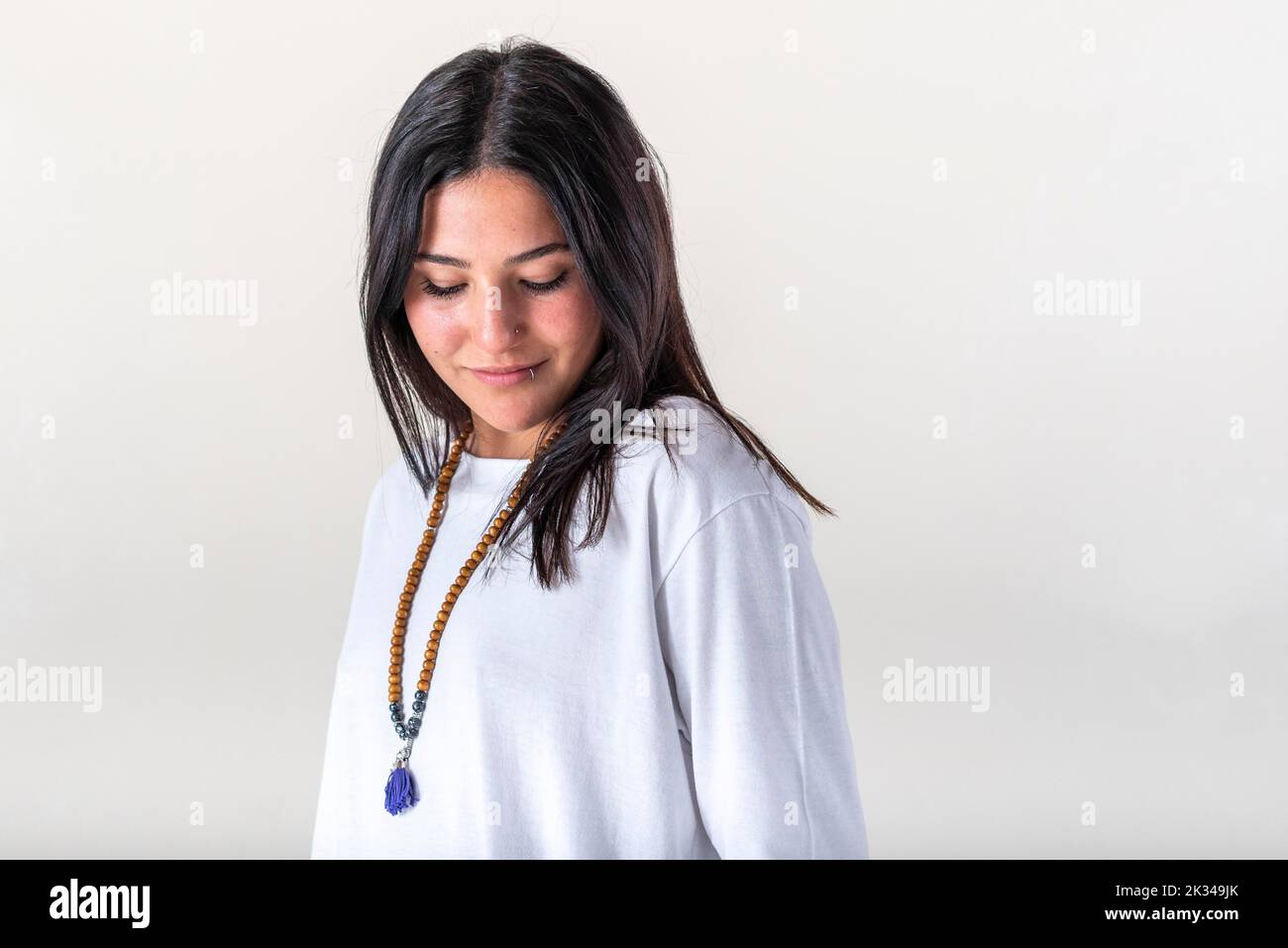 Portrait of a young woman dressed in white yoga clothes over white background wearing a japa ...