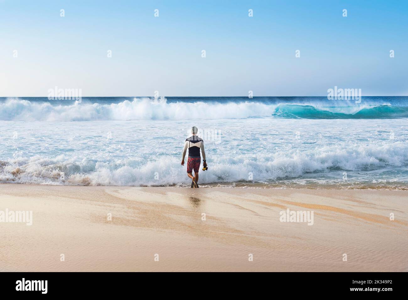 A surf photographer coming into the sea at Banzai Pipeline, Oahu ...