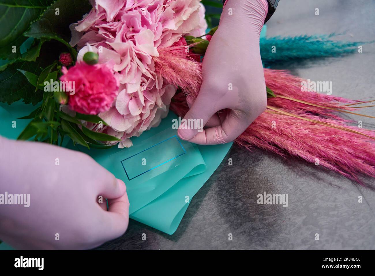 Hands in pink gloves are packing flowers Stock Photo - Alamy