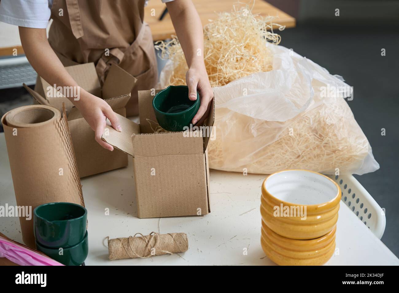 Woman putting green ceramic cup into cardboard box Stock Photo - Alamy