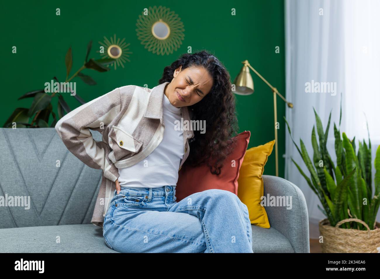 Young beautiful hispanic woman at home having severe back pain ...