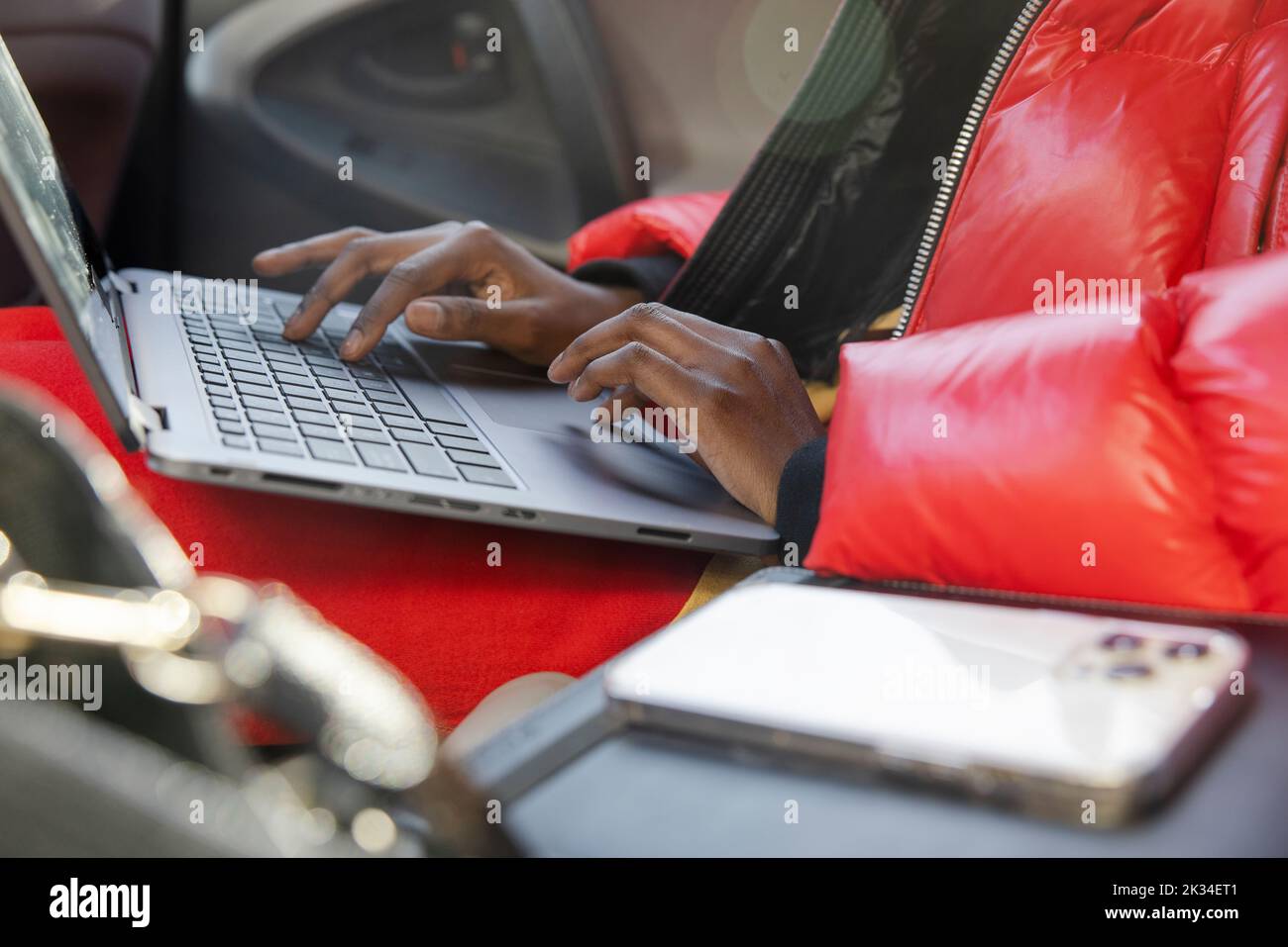 Close up woman in red coat using laptop in back seat of car Stock Photo ...