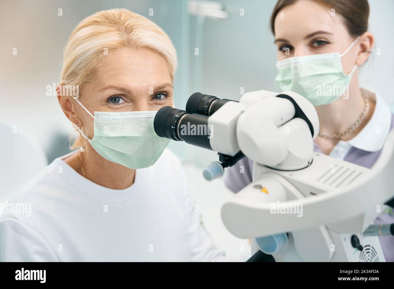 Team of experienced doctors examine under a microscope Stock Photo - Alamy