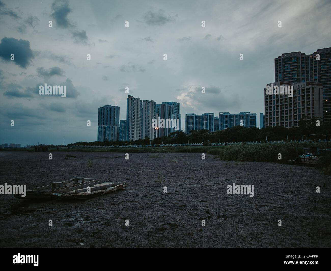 A muddy beach with seaside modern buildings under a cloudy sky Stock ...