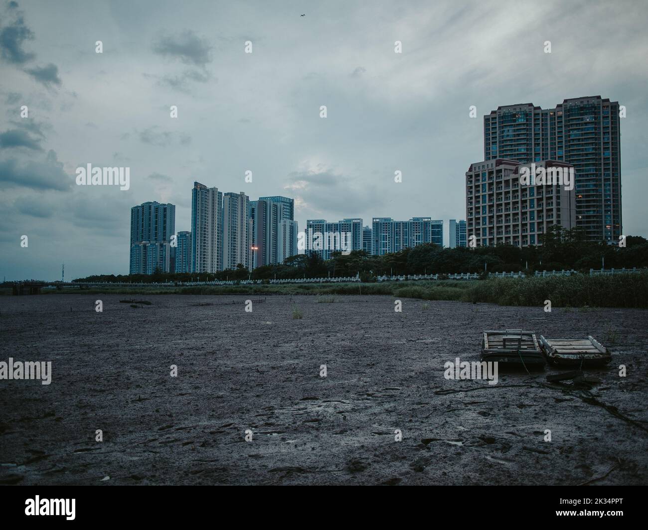 A Muddy beach with seaside modern buildings under a cloudy sky Stock ...