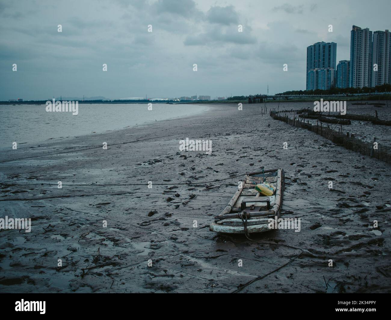 A Muddy beach with seaside modern buildings under a cloudy sky Stock ...