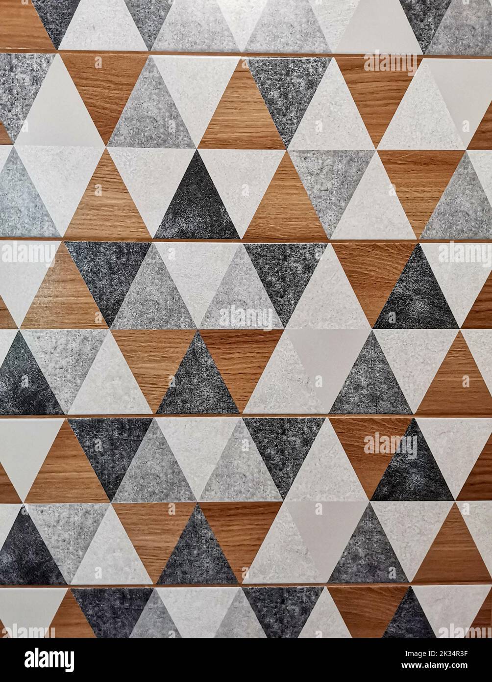 Ceramic tiled wall detail with textured triangles pattern of neutral ...