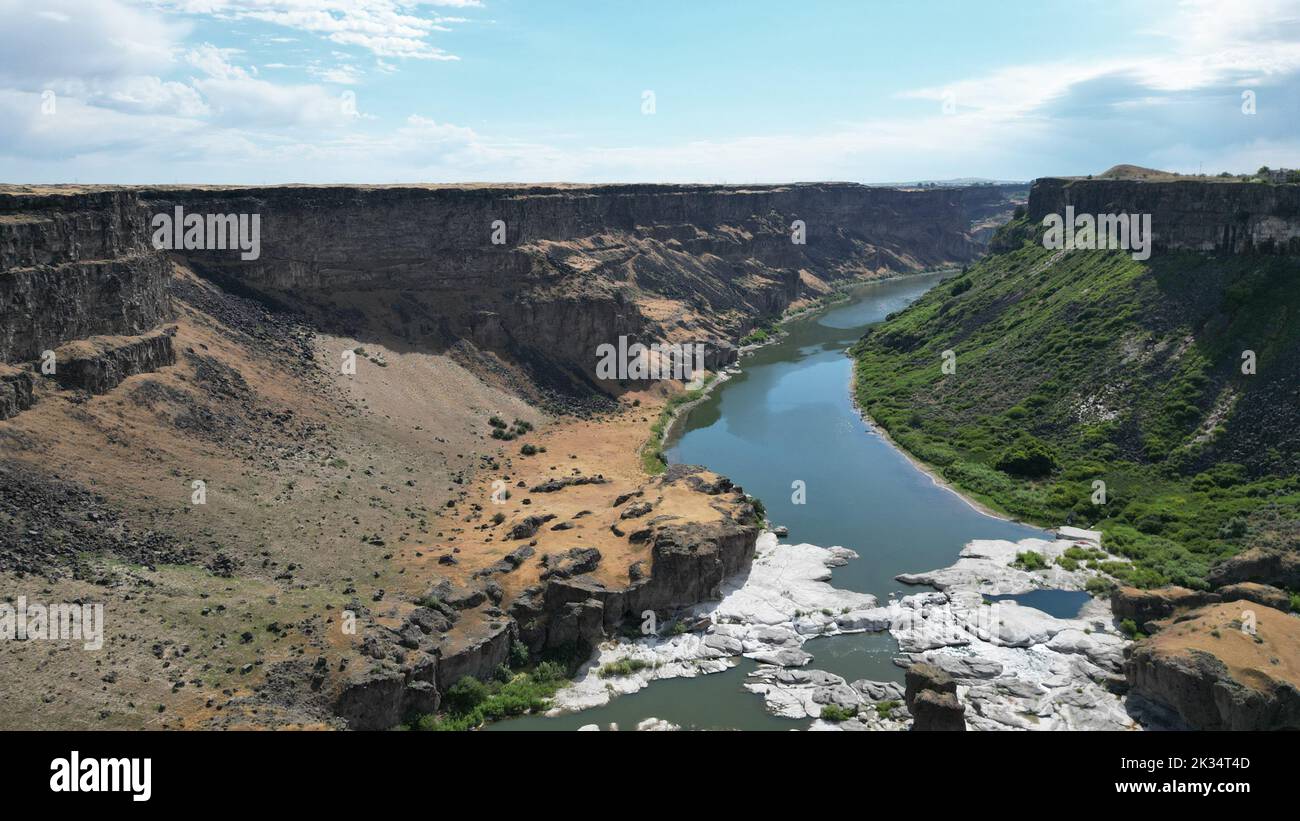 A beautiful landscape of a river flowing among forested cliffs under a ...