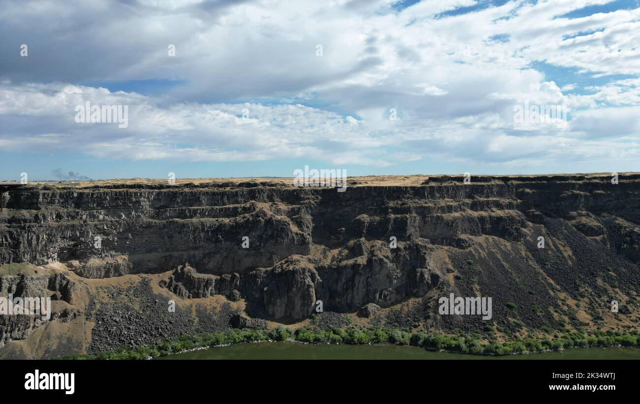 A beautiful landscape of rocky cliffs under a cloudy sky with a river ...