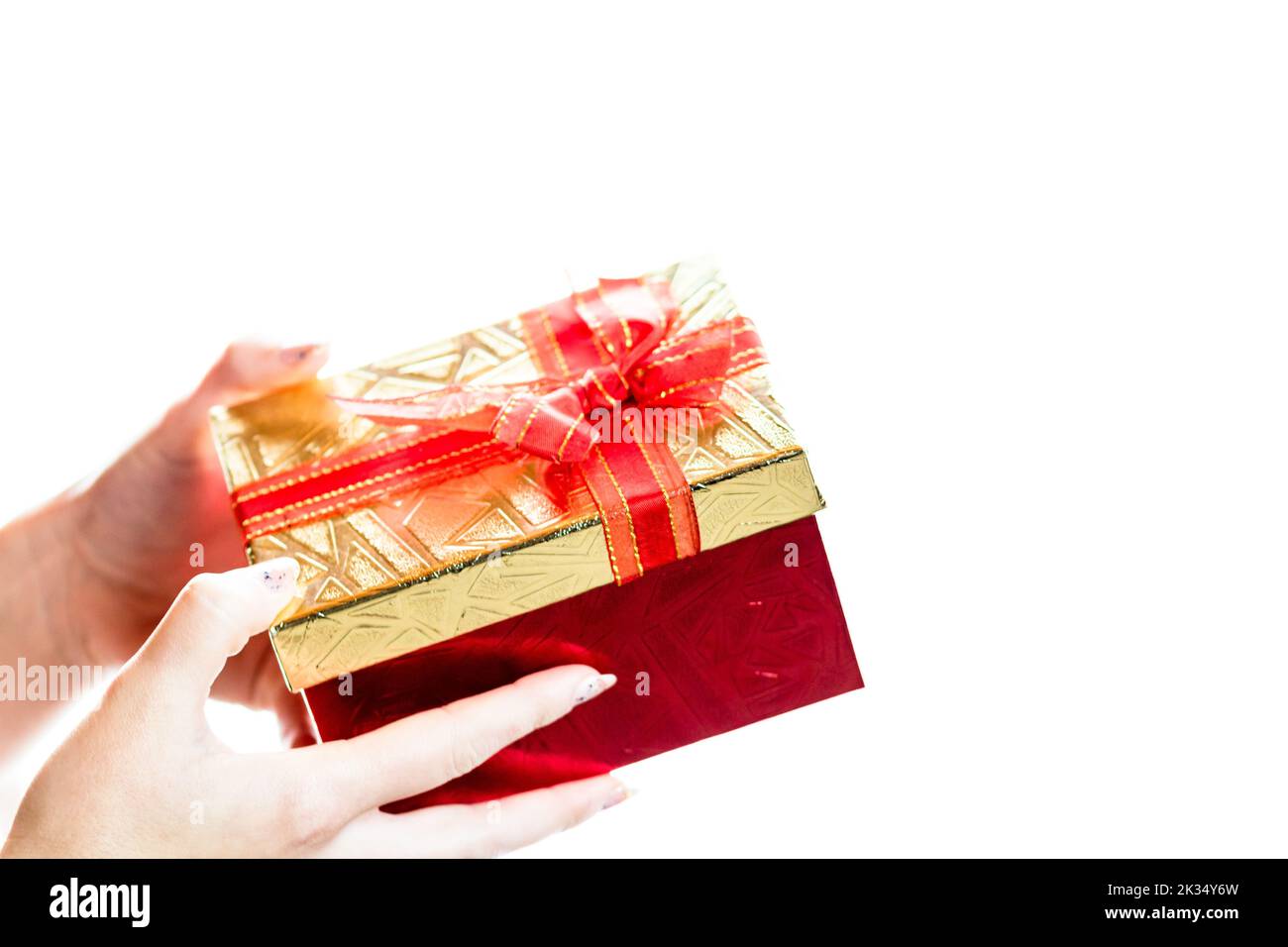 Hand showing a present box with a red ribbon isolated on white ...