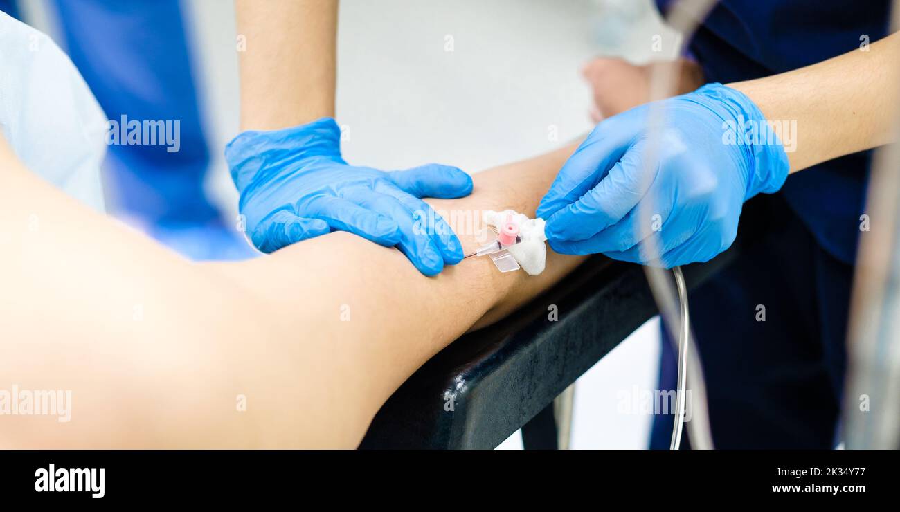 Installing a butterfly catheter in a patient's arm in a hospital. The ...