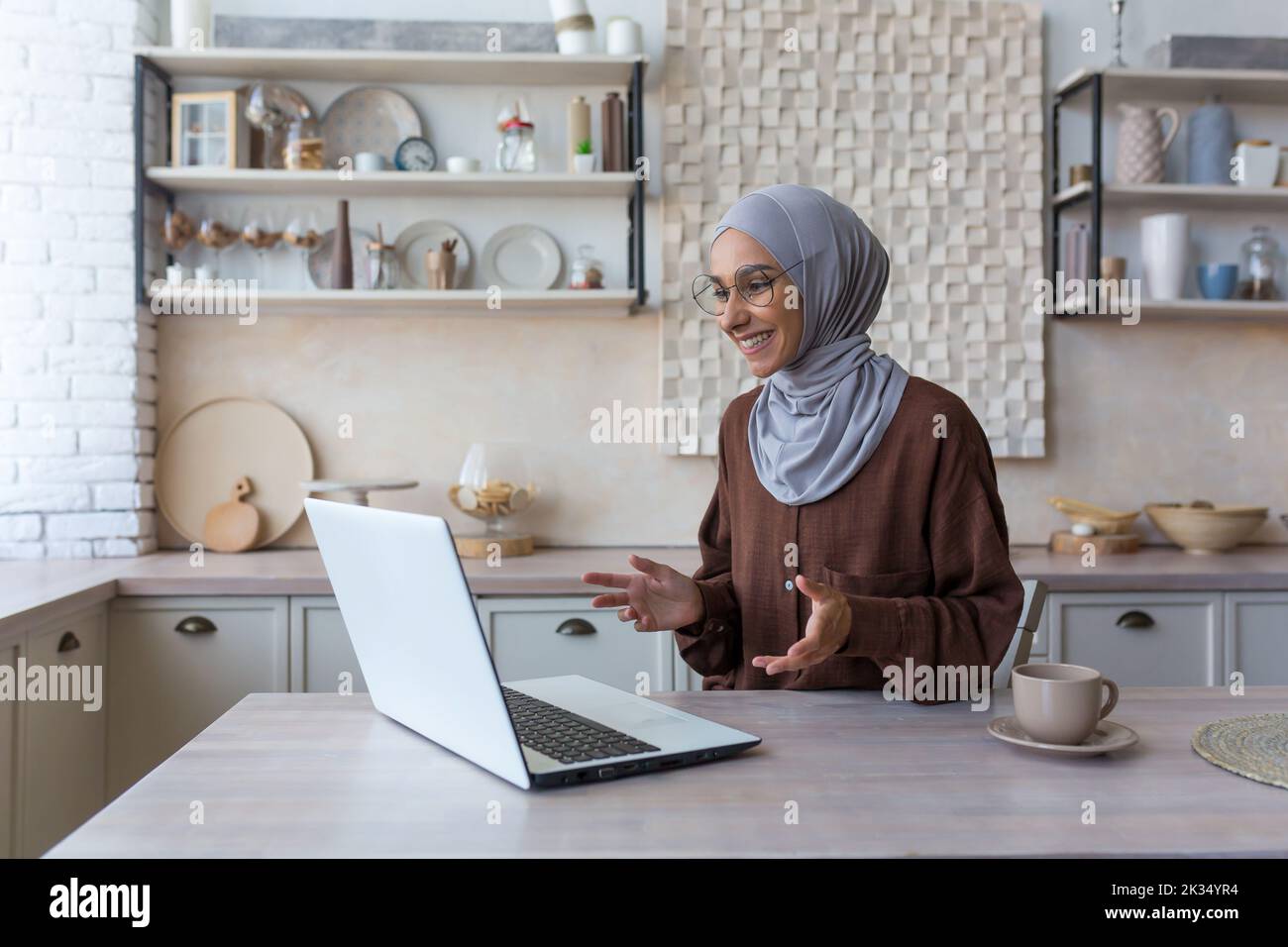 Young beautiful Muslim woman in hijab using laptop for video call ...