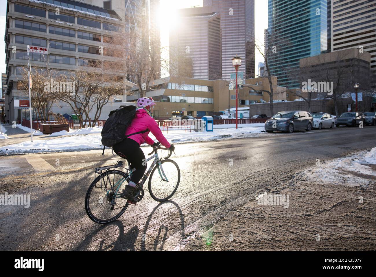 Female bike courier with bag riding bike on sunny winter city street ...