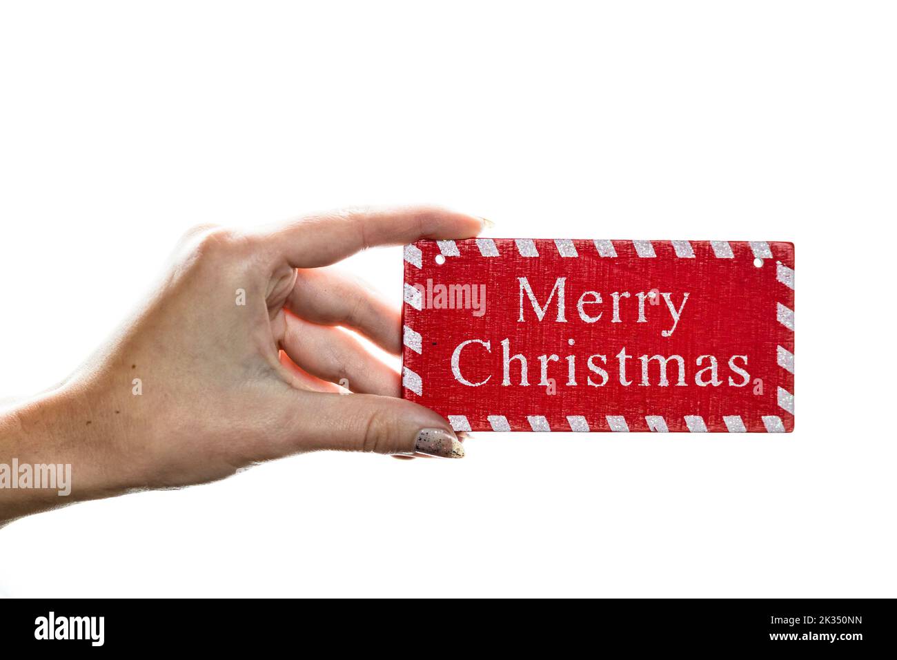 A hand holding a wooden red ornament with the text "Merry Christmas ...