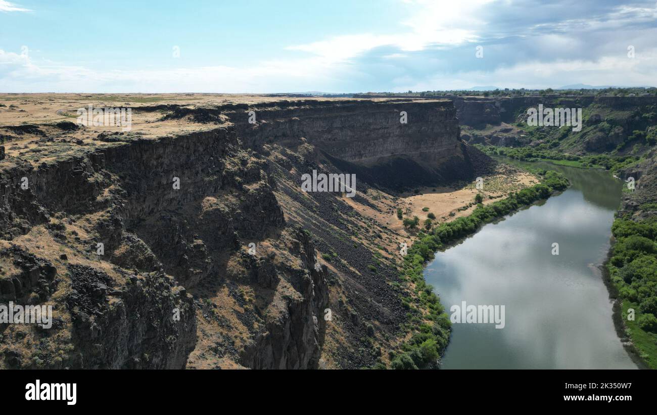 A bird's eye view of a steep cliff and river surrounded by vegetation ...