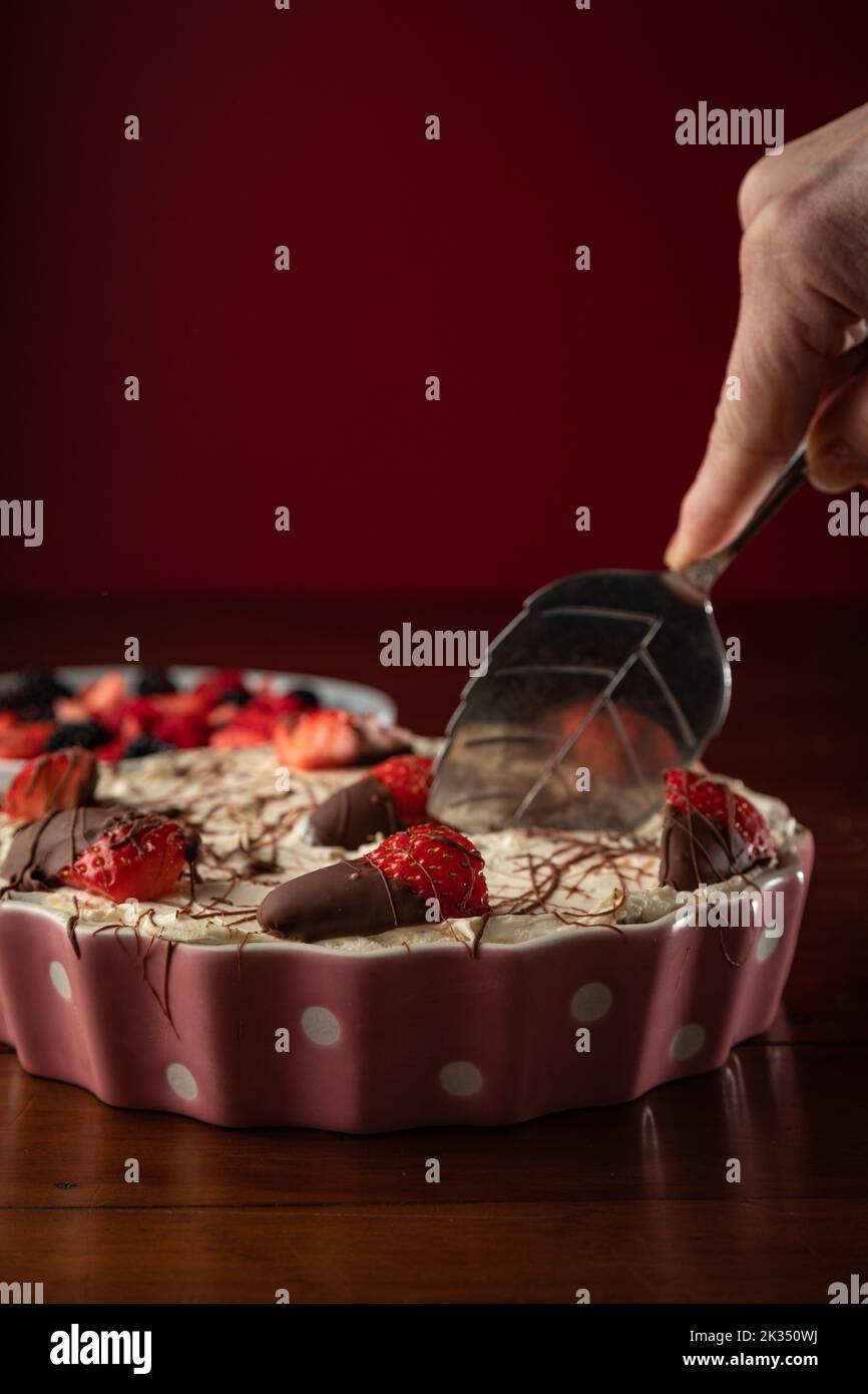 A vertical shot of a tasty cheesecake with different kinds of berries ...