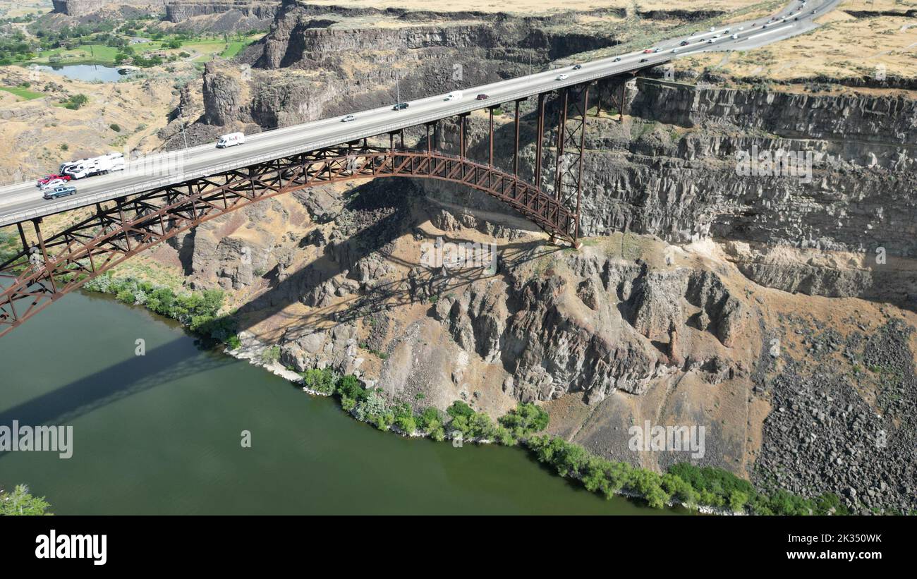 A bird's eye view of a bridge going over a river and a steep cliff on a ...