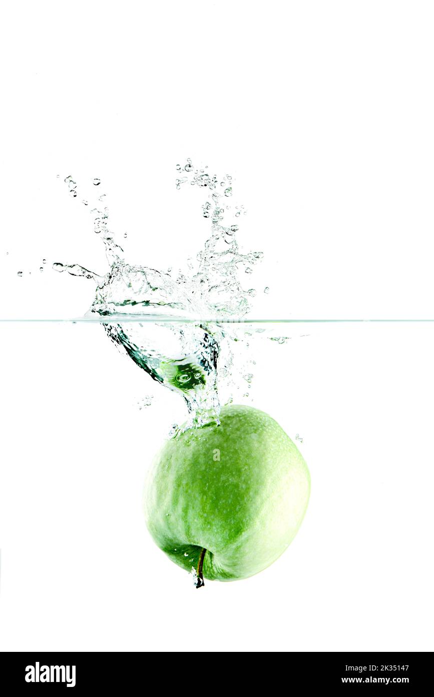 A green apple falling into water splash on a white background Stock ...