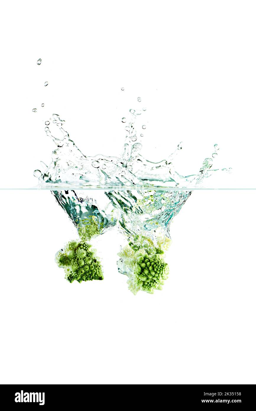 A broccoli piece falling into water splash in a white background Stock ...