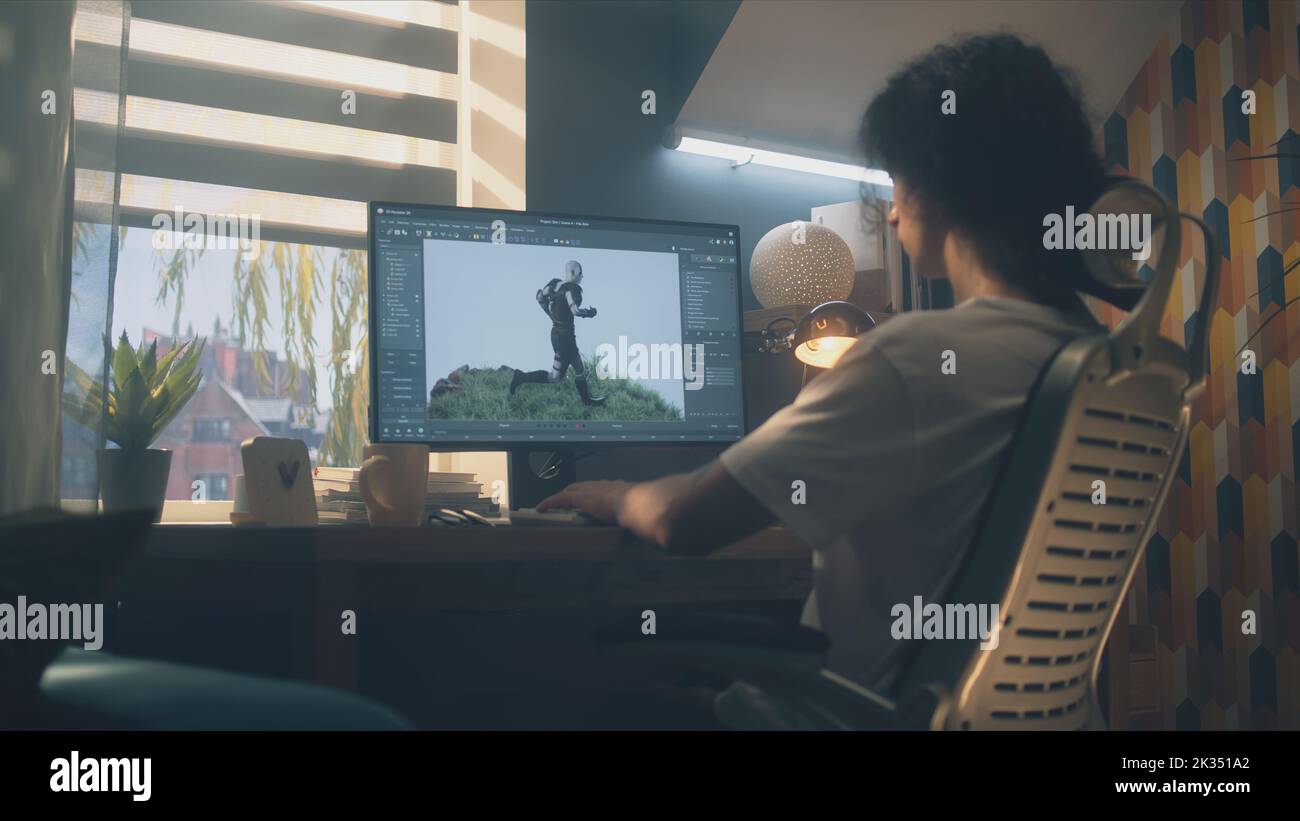 Male 3D designer sitting at the table at home and making animation for ...