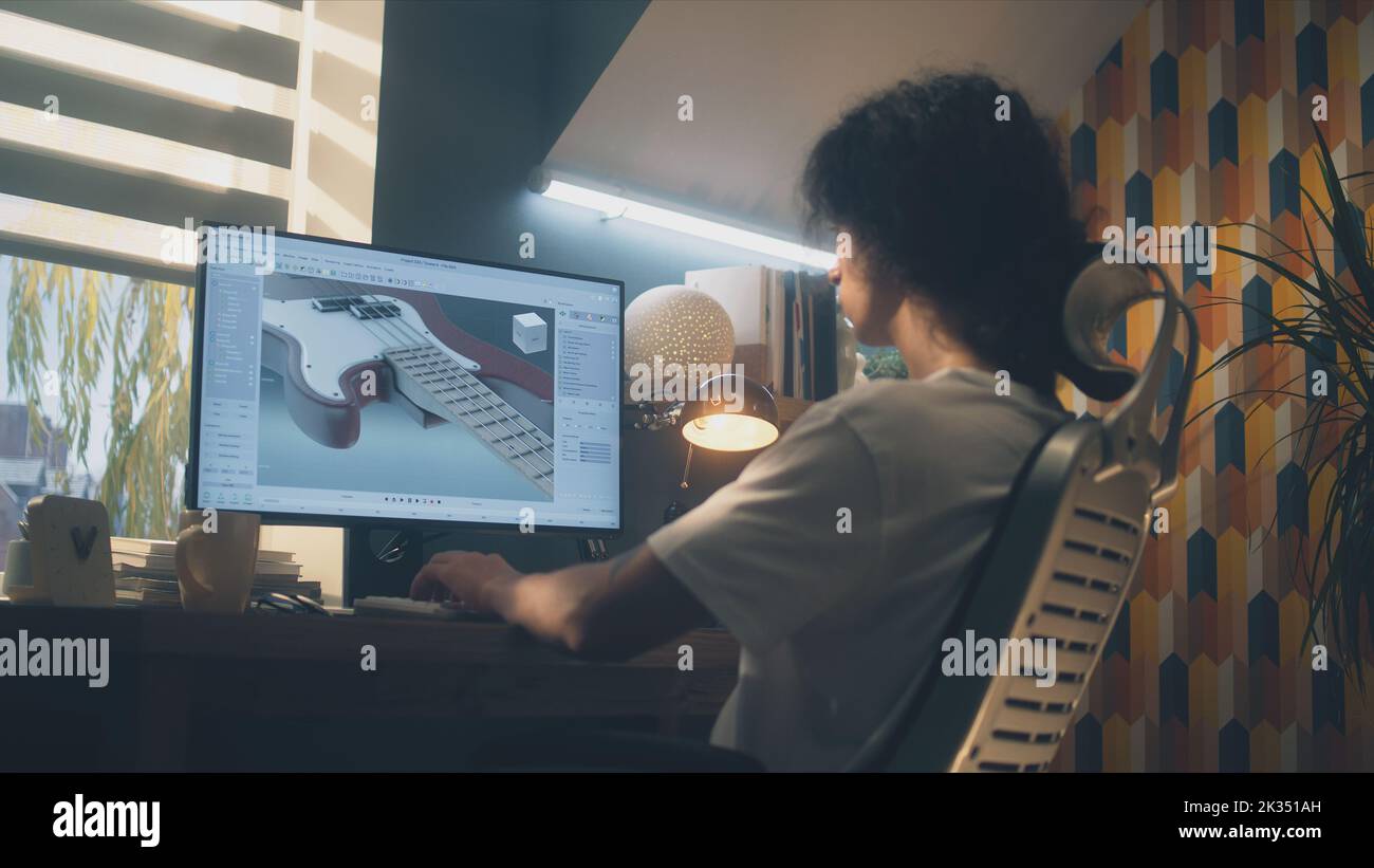 Young guy creating 3D prototype of guitar using modern personal computer and 3D modeling program ...