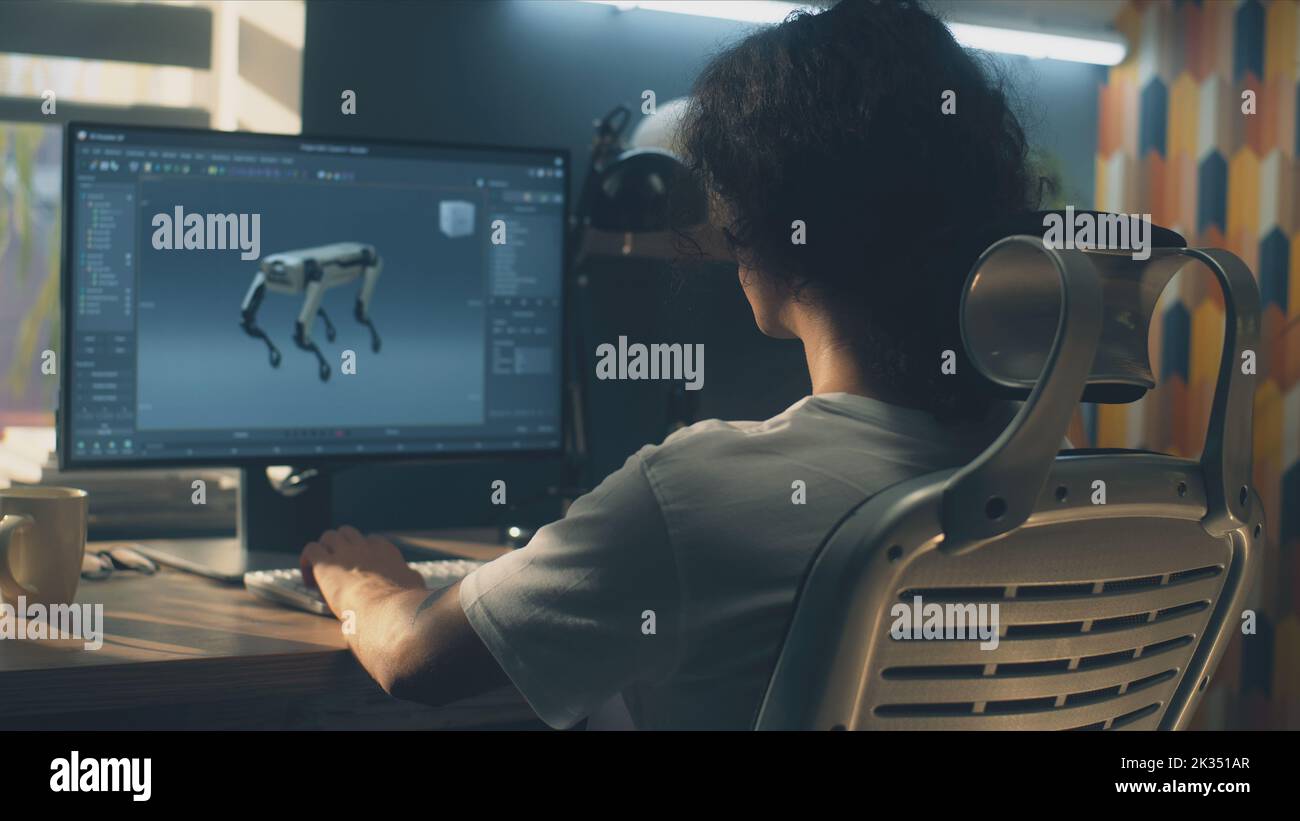 Man sitting at the table and creating 3D prototype of modern robot while working on pc in 3D ...