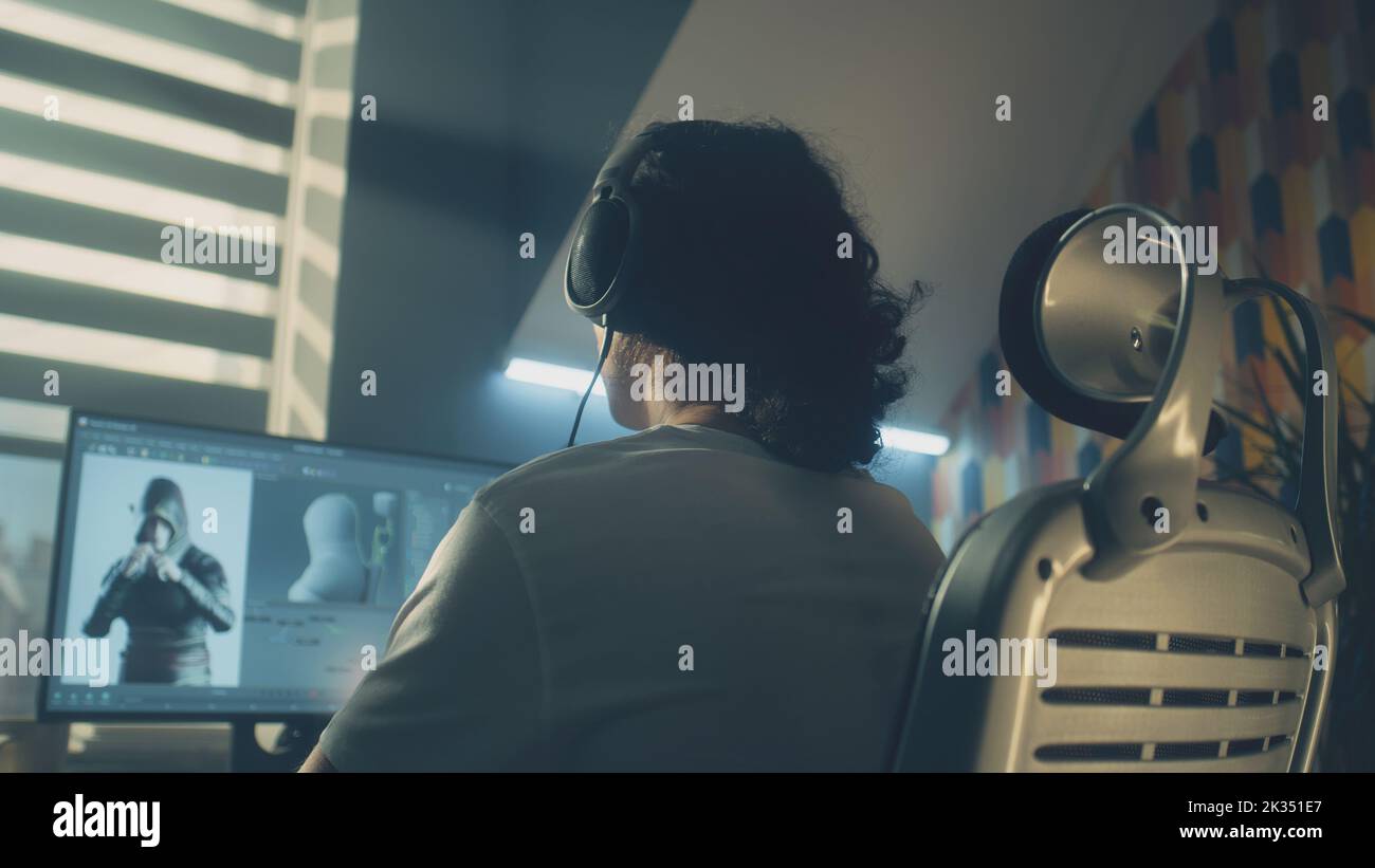 Man in headphones creating video game character in 3D modeling program ...